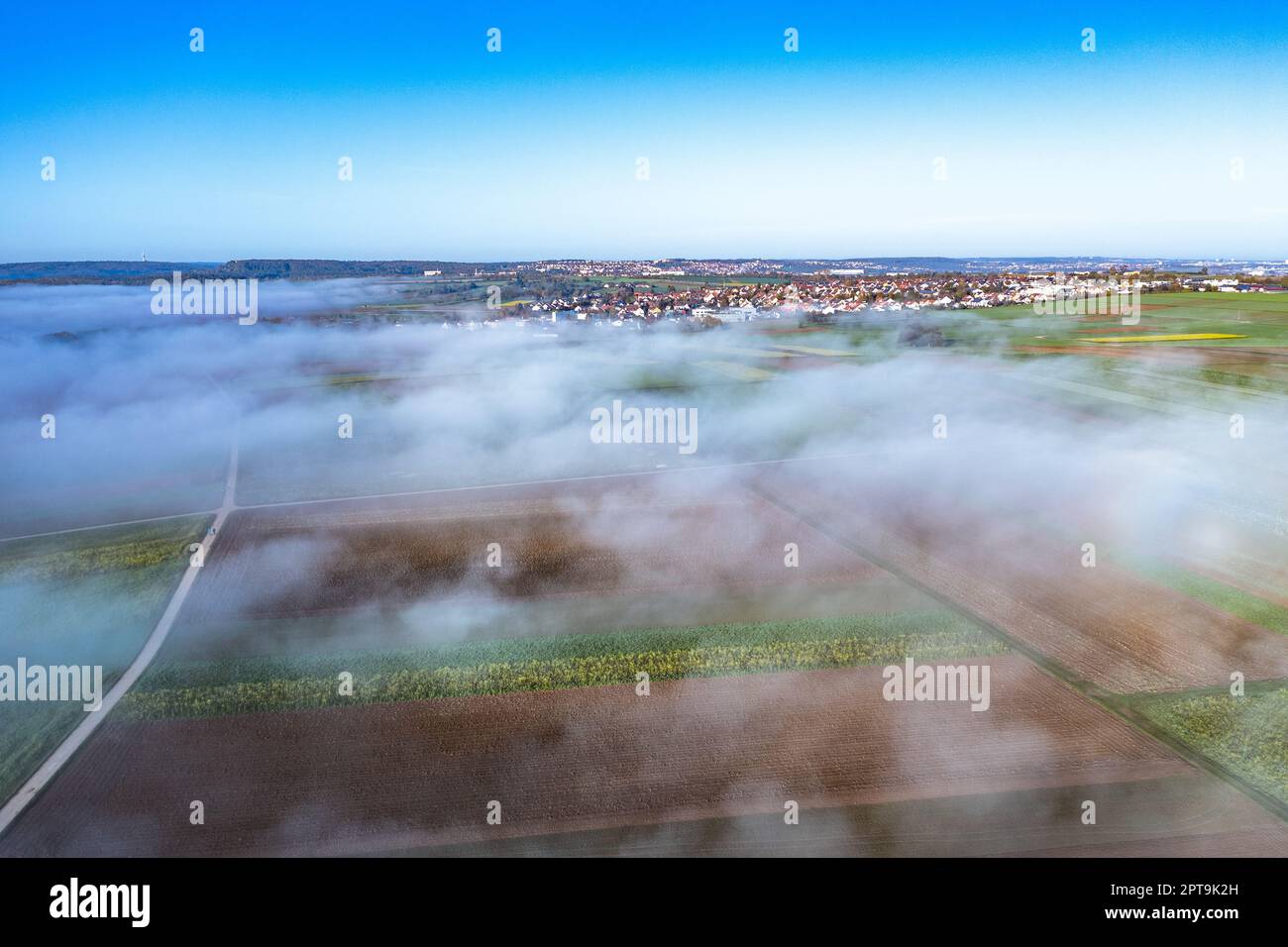 landscape aerial view of fog over fields and village in background ...
