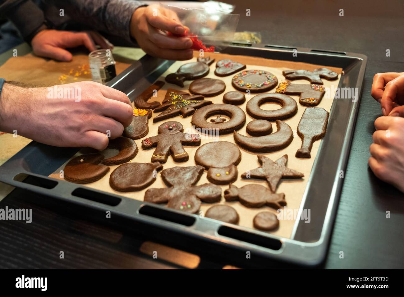 A group of friends prepares ginger cookies of different shapes before ...
