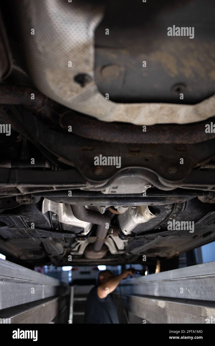 Car mechanic under a car in a repair shop/car garage (shallow DOF/color ...