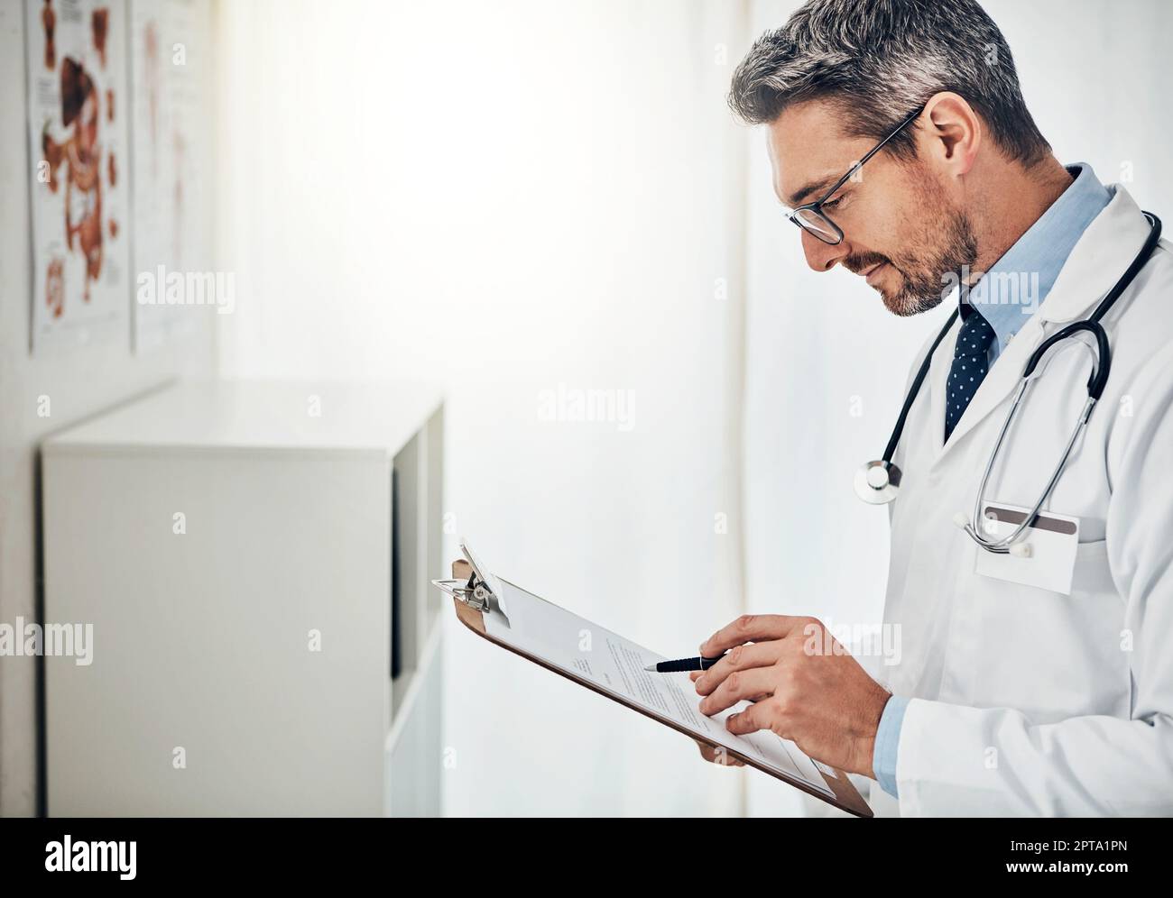 Checking up on his patients progress. a focussed doctor reading a ...