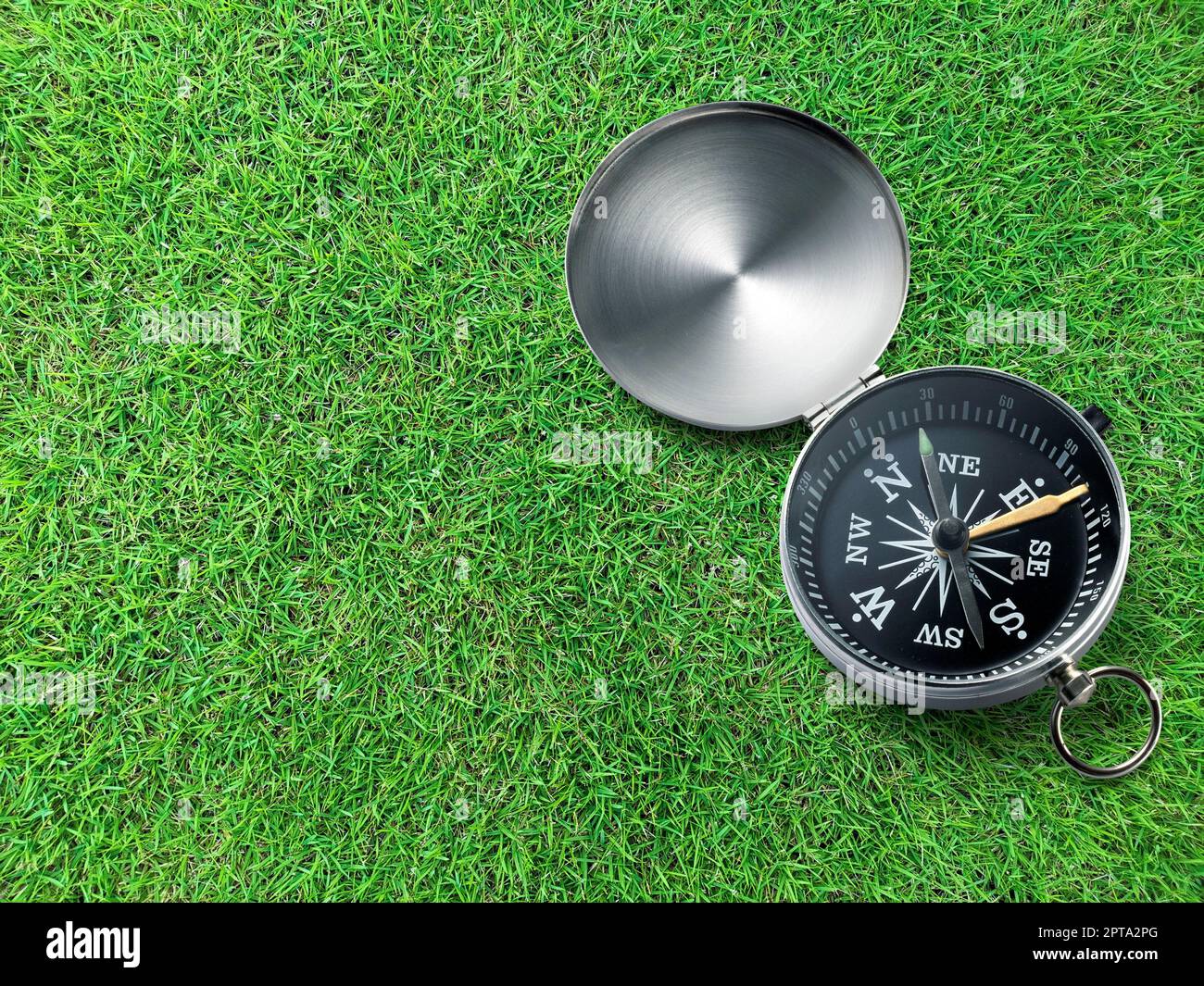Compass on Green field of grass background. Travel destination and ...