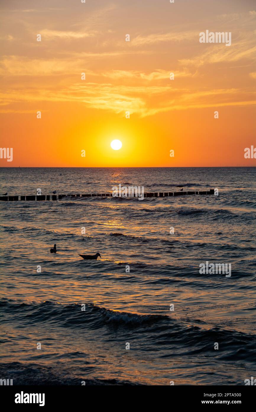 Beach Idyll - Beautiful orange sunset over the sea, with a wooden ...