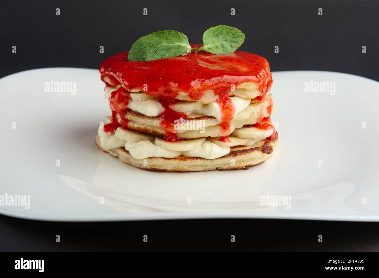 Pile of flapjacks with strawberry jam and banana Stock Photo - Alamy