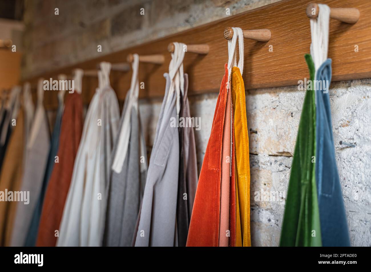 Selective focus on colourful fabrics hanging on hanger on brick wall ...
