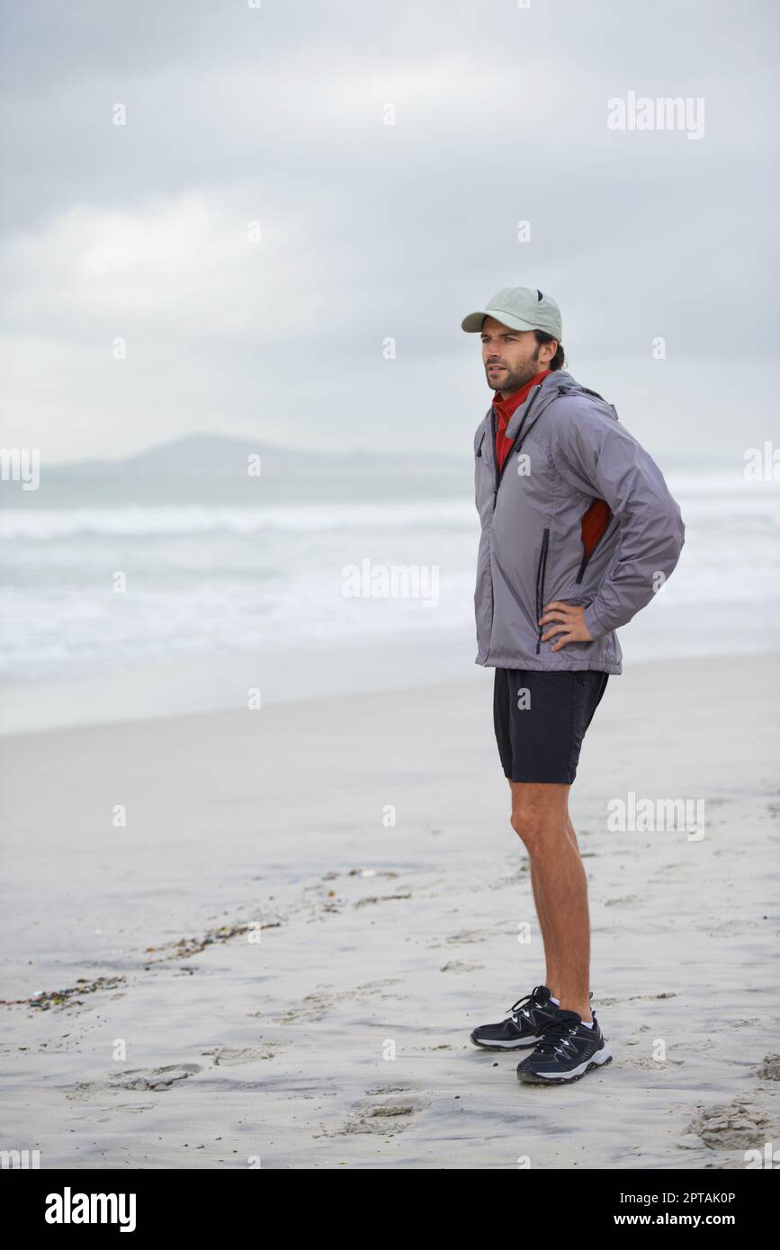 Taking a morning run on the beach. Full length shot of a handsome young ...