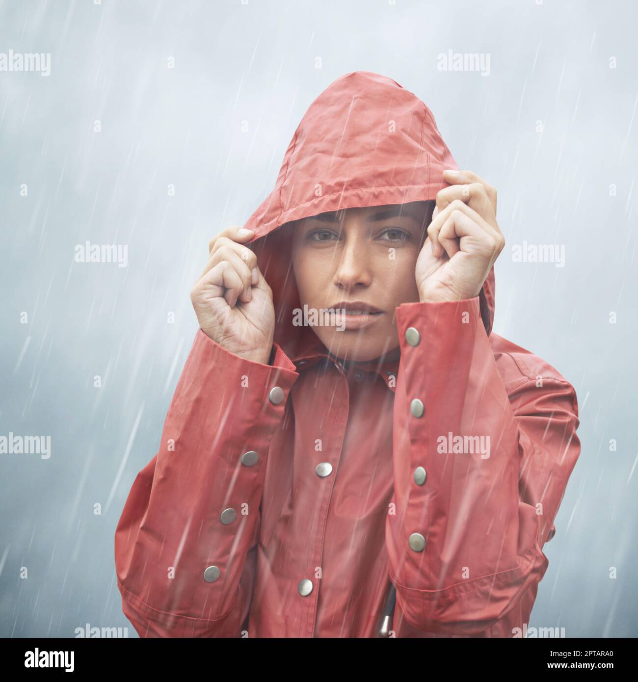 Gray skies. Cropped portrait of a young young woman pulling up her hood ...