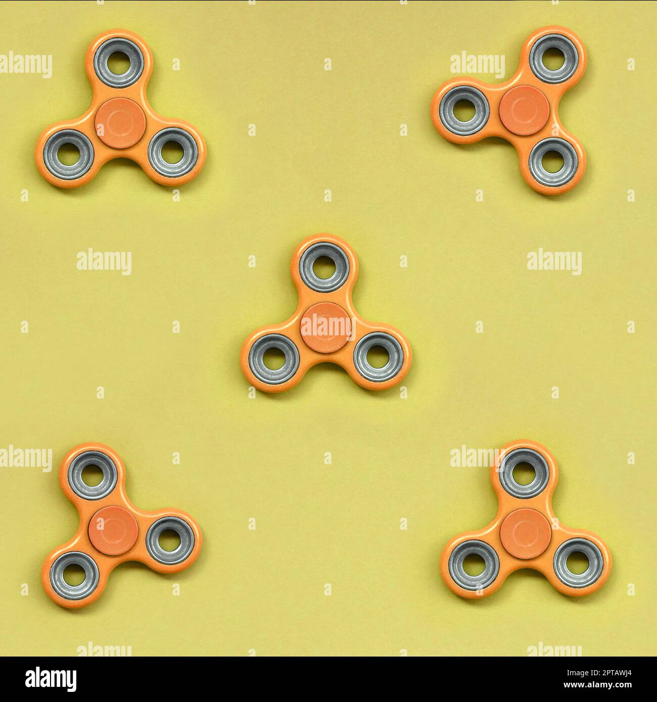 Many orange fidget spinners lies on texture background of fashion ...