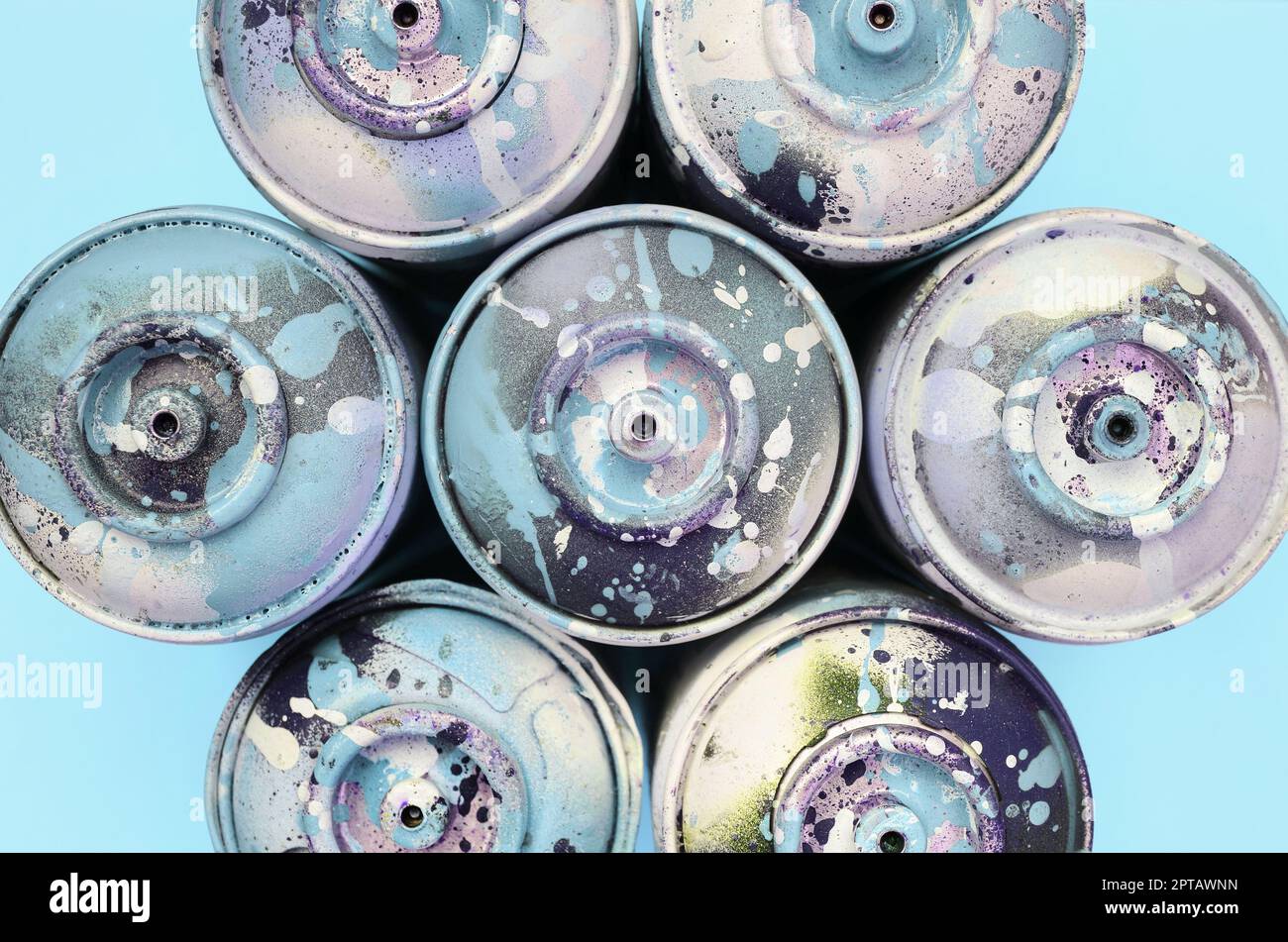 A few used spray cans with blue paint drips lie on texture background ...