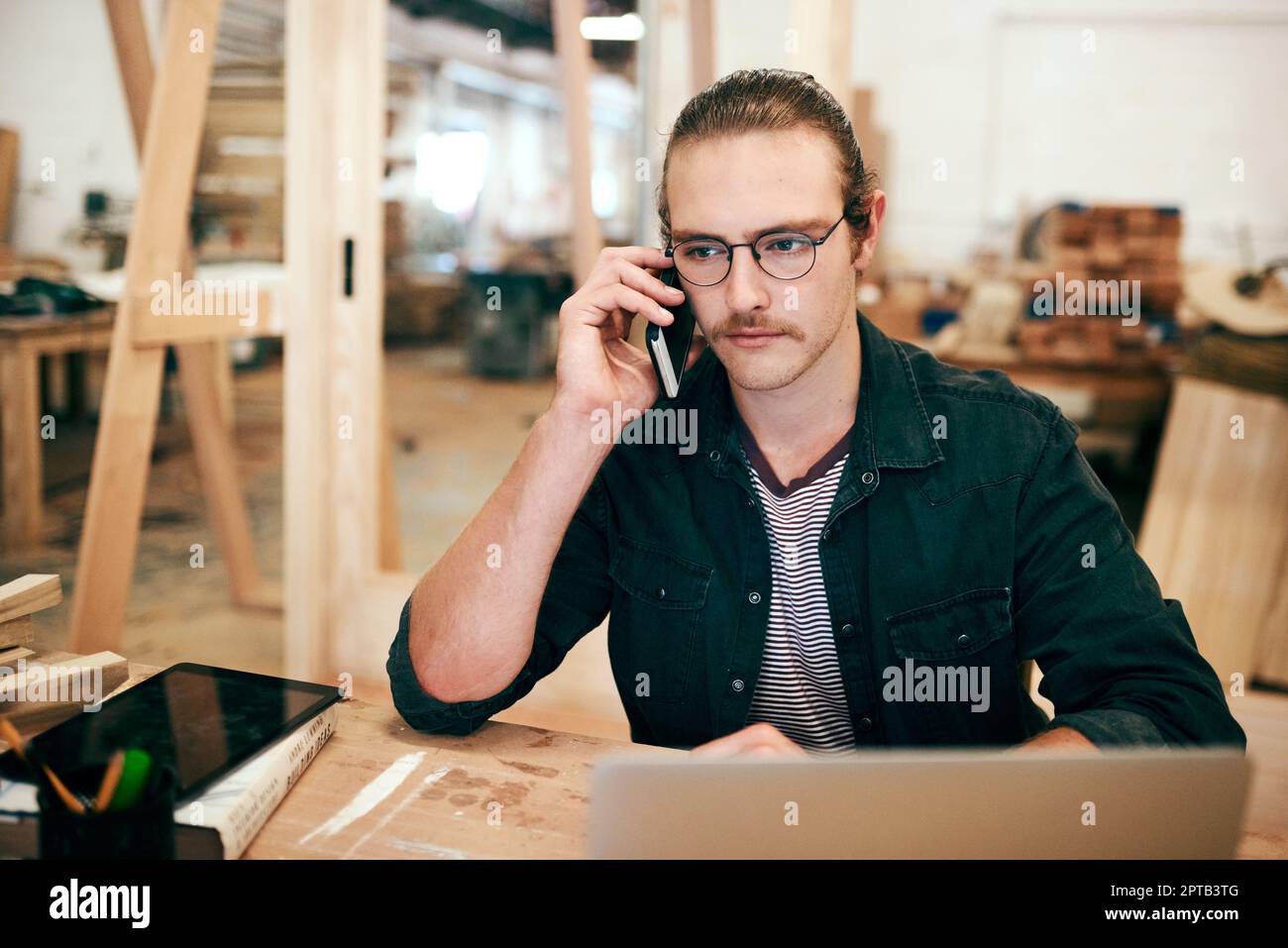 Im listening...a young carpenter making a phone call while working ...