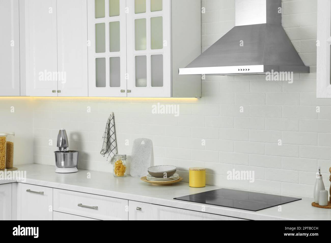 Elegant kitchen interior with modern range hood over cooktop and ...