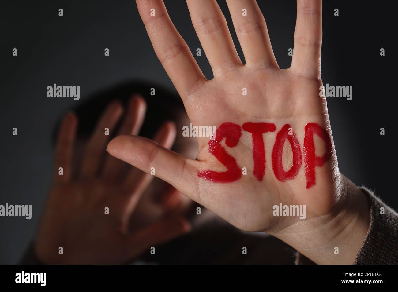 Woman with word Stop written on hand against black background, closeup ...