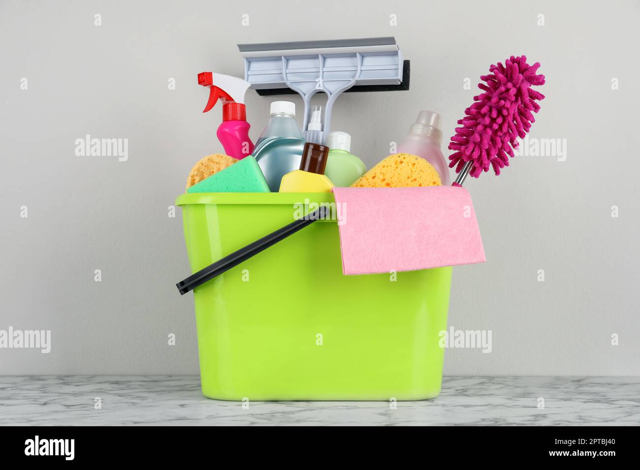 Light green bucket with cleaning products on marble table Stock Photo ...