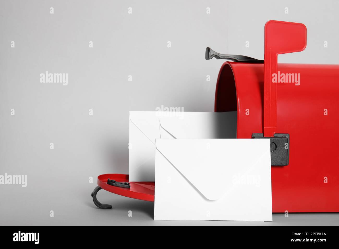 Open red letter box with envelopes on light background, closeup. Space ...