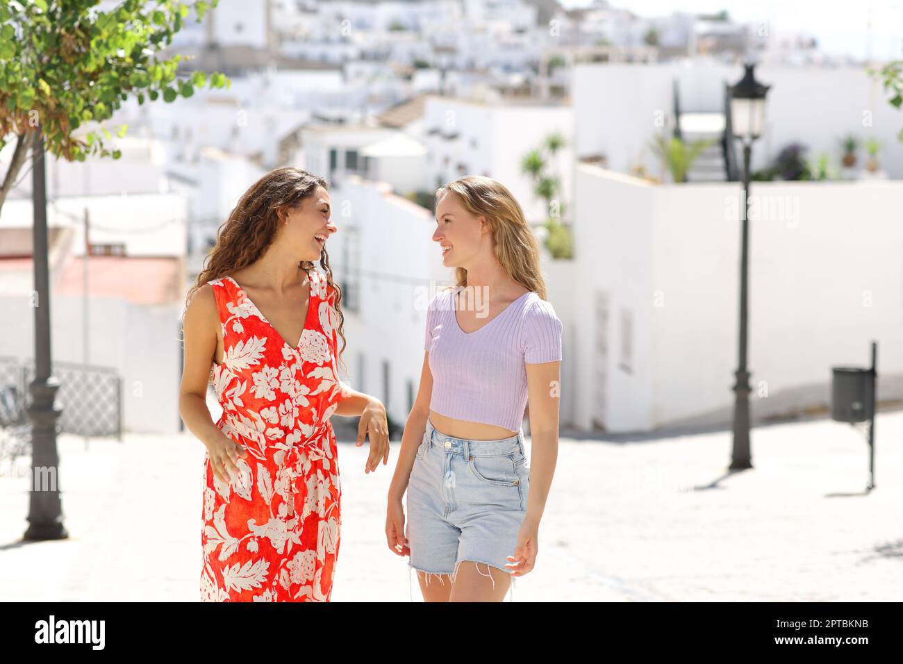 Two friends talking in the street in a white town on summer vacation ...