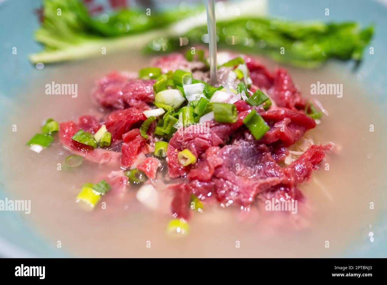 Boiling hot soup pour into noodle with slice of raw beef, famous ...