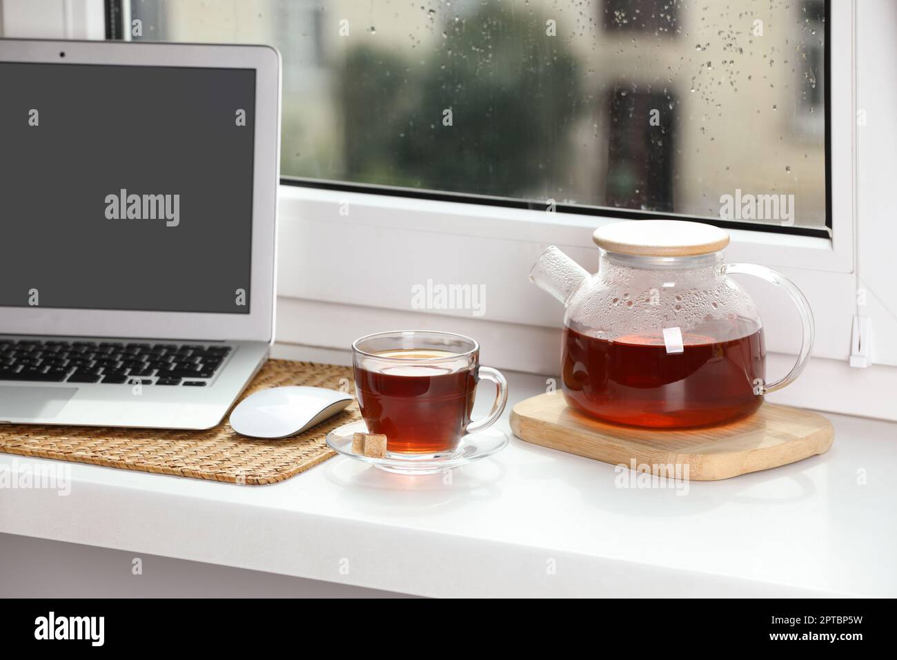 Modern laptop and tea on white sill near window Stock Photo - Alamy