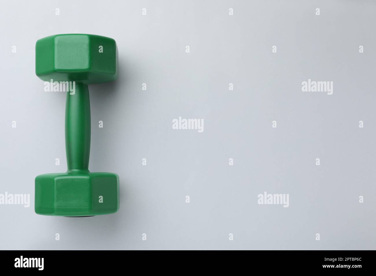 Green vinyl dumbbell on light background, top view. Space for text ...
