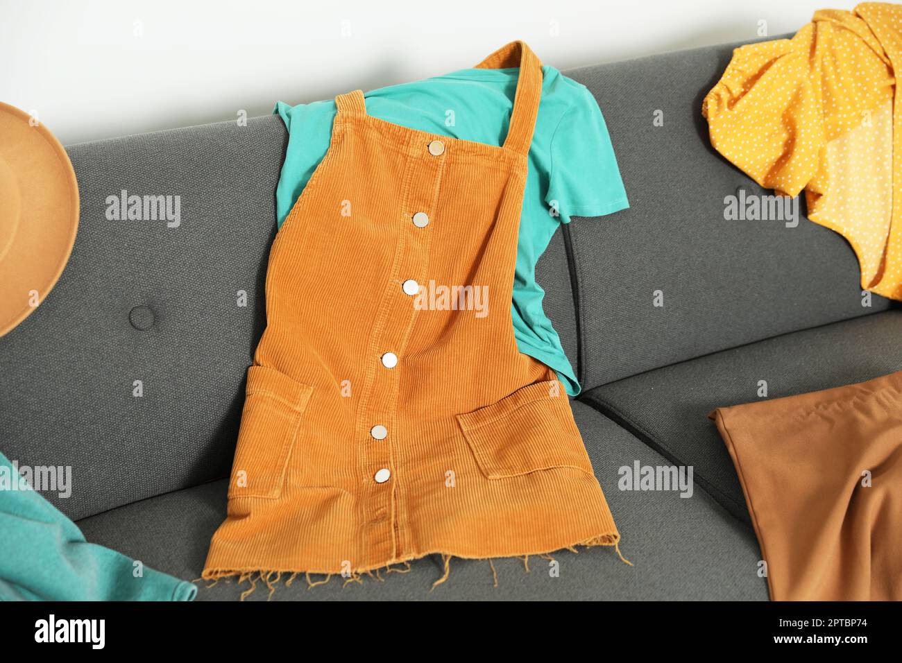 Messy pile of clothes on sofa in living room Stock Photo - Alamy