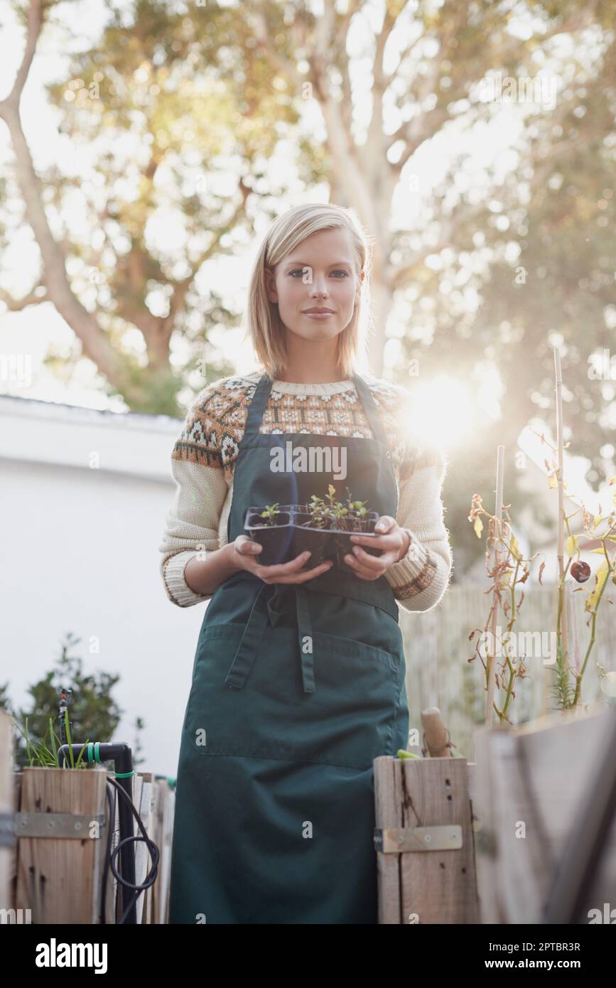 Giving back to the earth. A young gardener outside in a nursery Stock ...