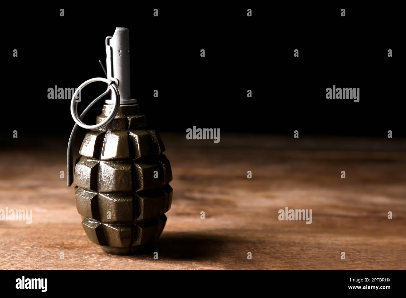 Hand grenade on wooden table against black background. Space for text ...