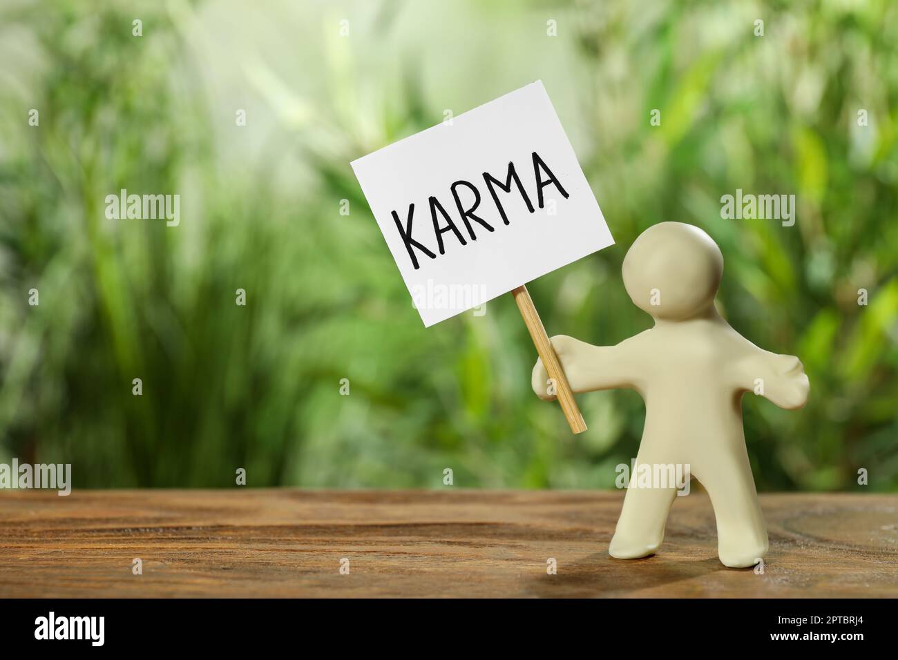 Human figure holding sign with word Karma on wooden table. Space for ...