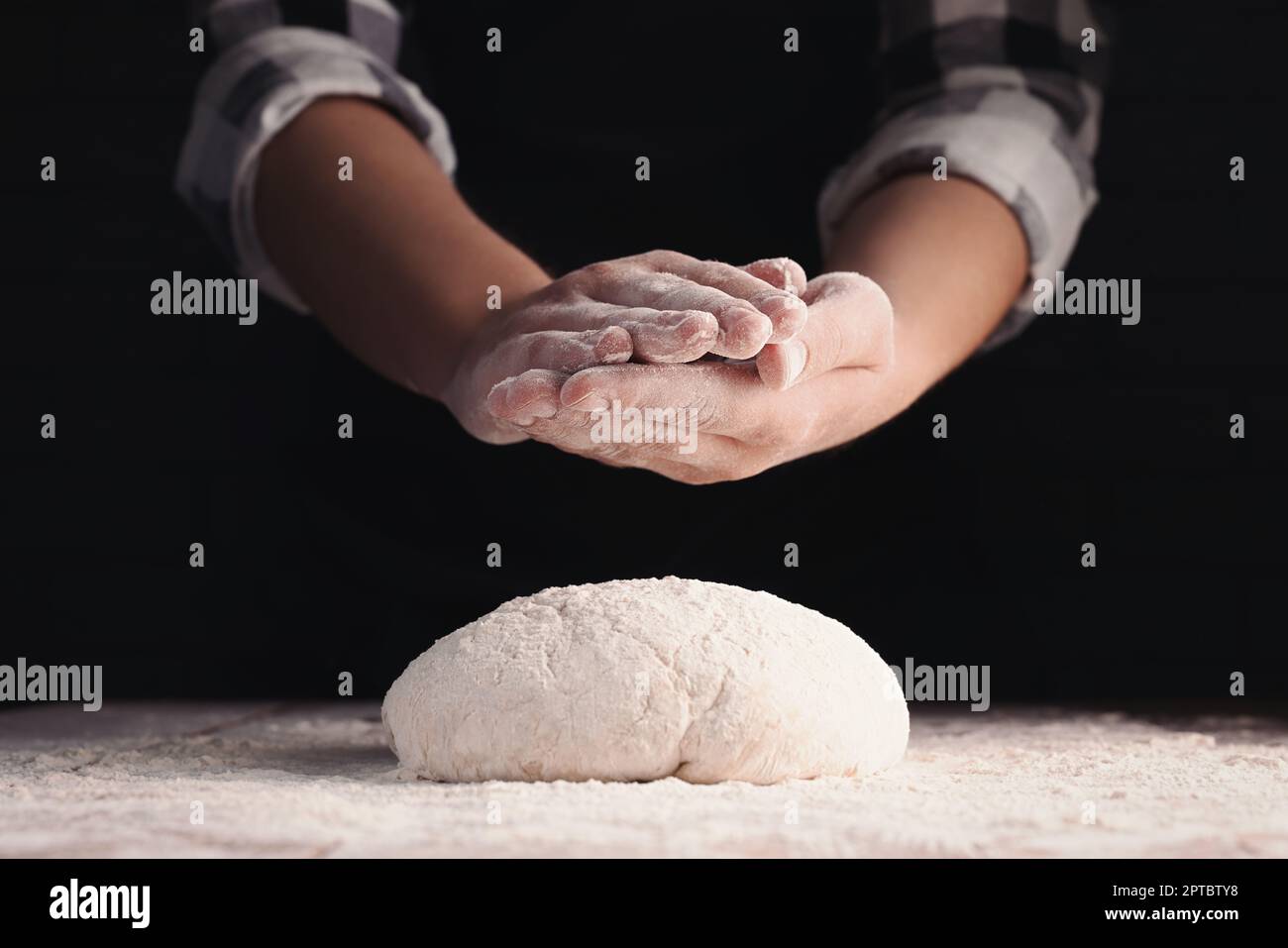Man making dough at table against black background, closeup Stock Photo ...