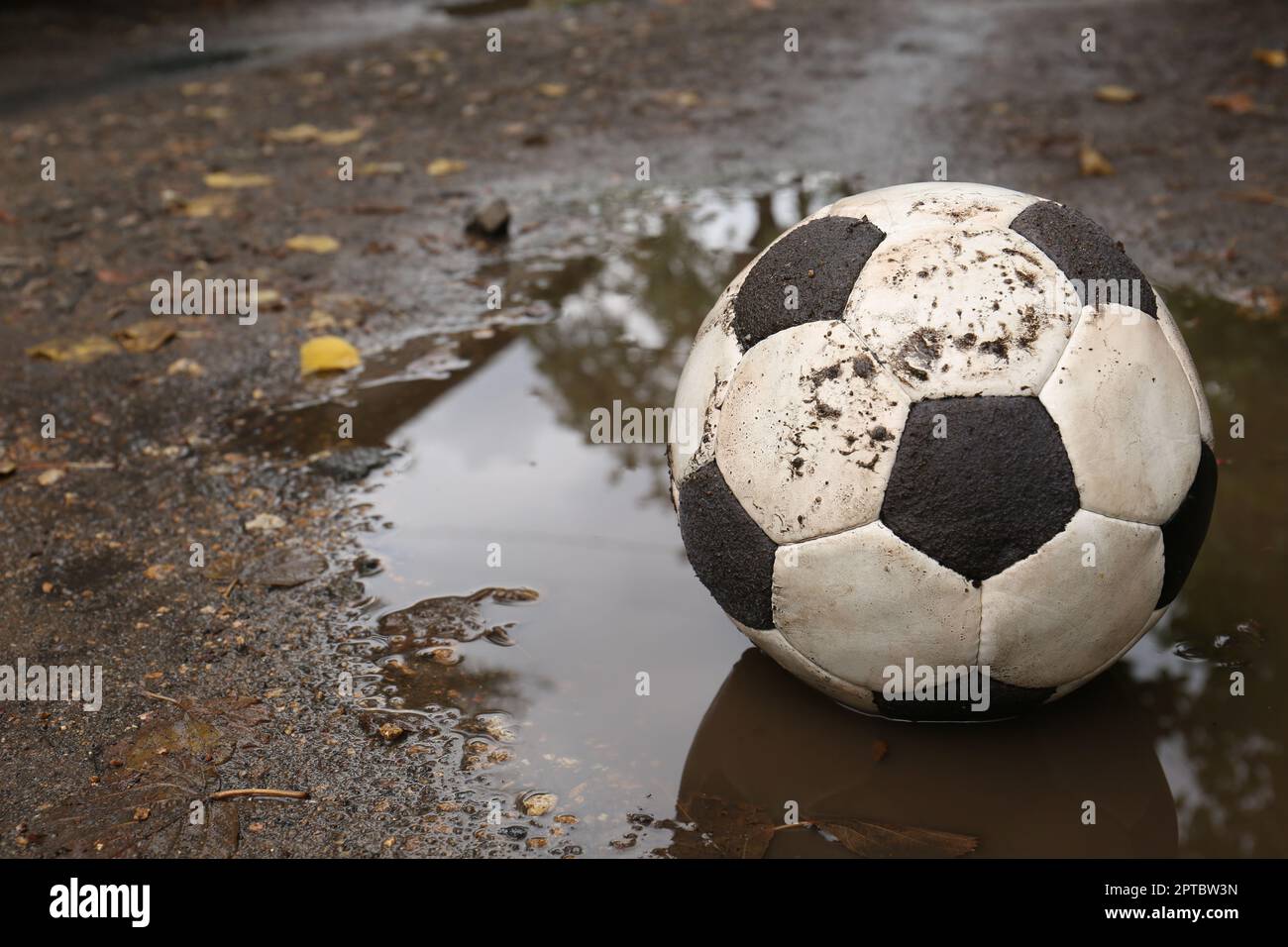 Dirty soccer ball in muddy puddle, space for text Stock Photo - Alamy