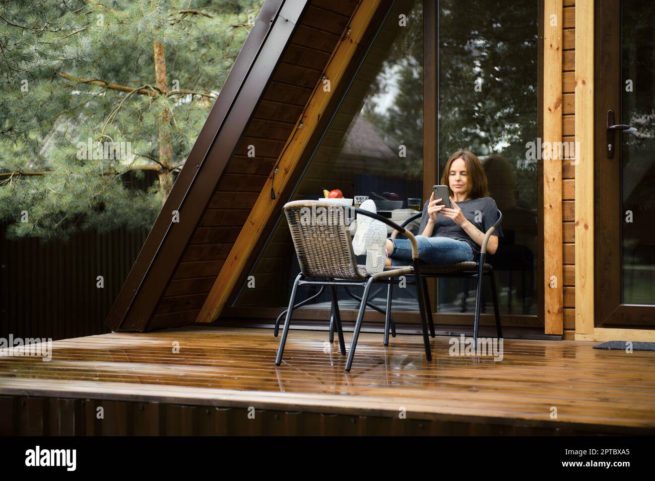 Cute woman with smartphone on terrace of her a-frame cabin Stock Photo ...