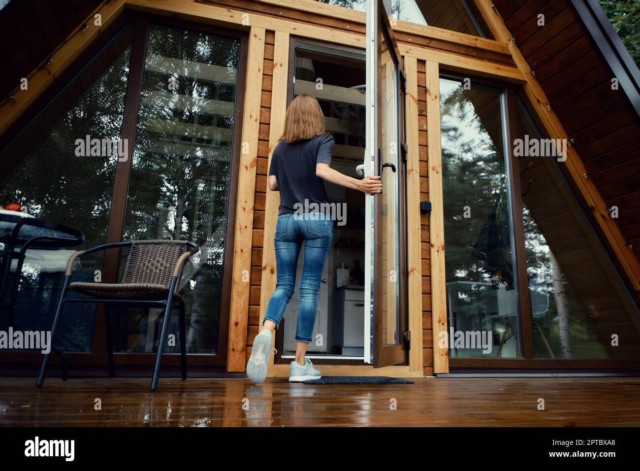Back view of a woman entering forest cabin Stock Photo - Alamy