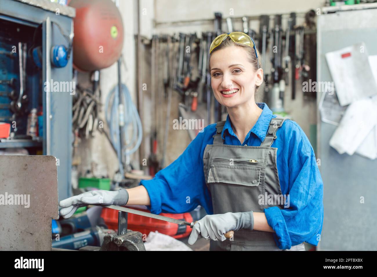 Female worker in metal workshop looking at camera being surrounded by ...