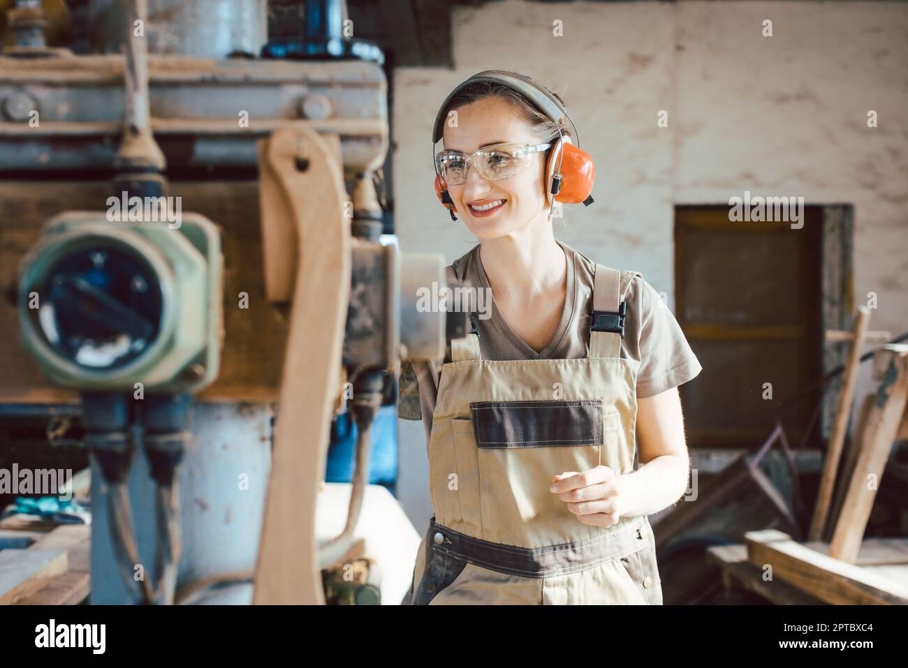 Woman carpenter in traditional carpentry adjusting the machine planer ...