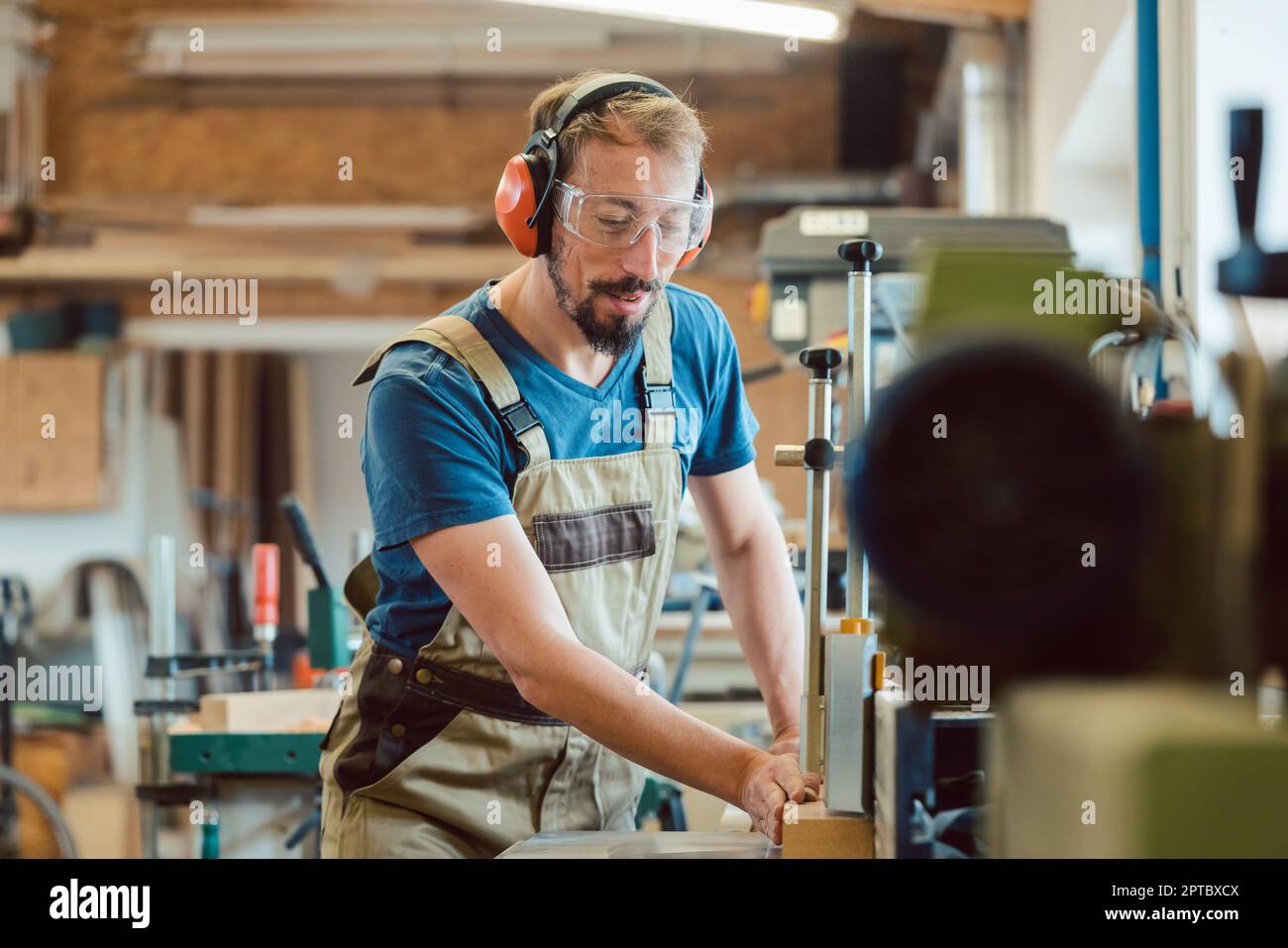 Absorbed carpenter with ear protection and safety goggles at the ...