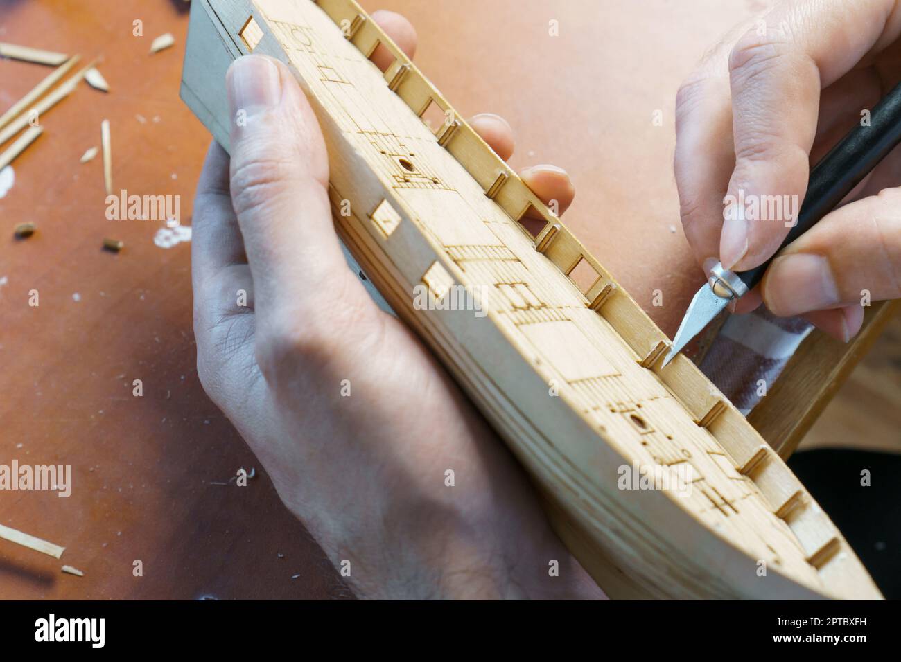 Hands of man cutting out details for ship model with clerical knife ...