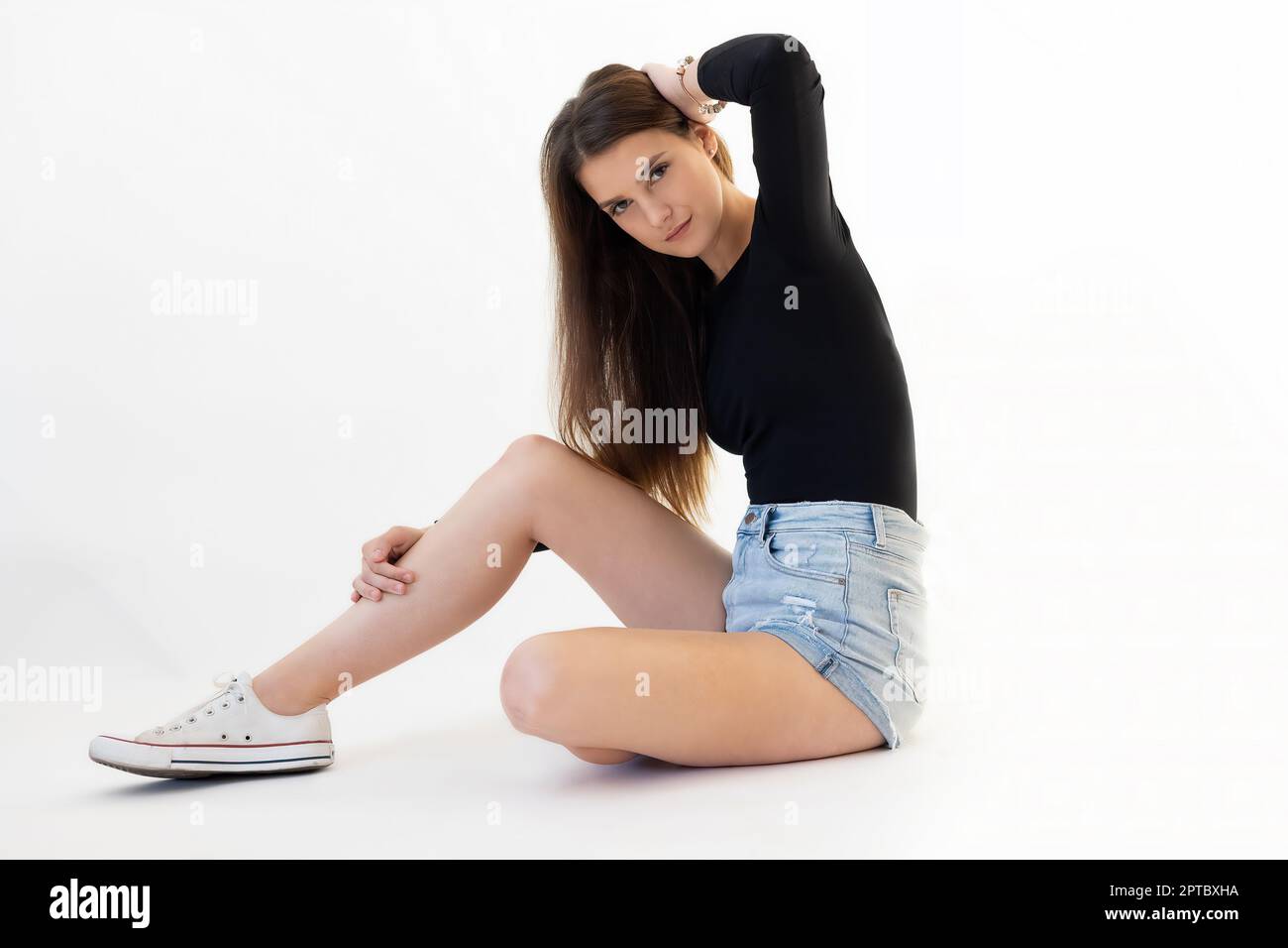 Young long haired and long legged woman is posing sitting on floor and ...