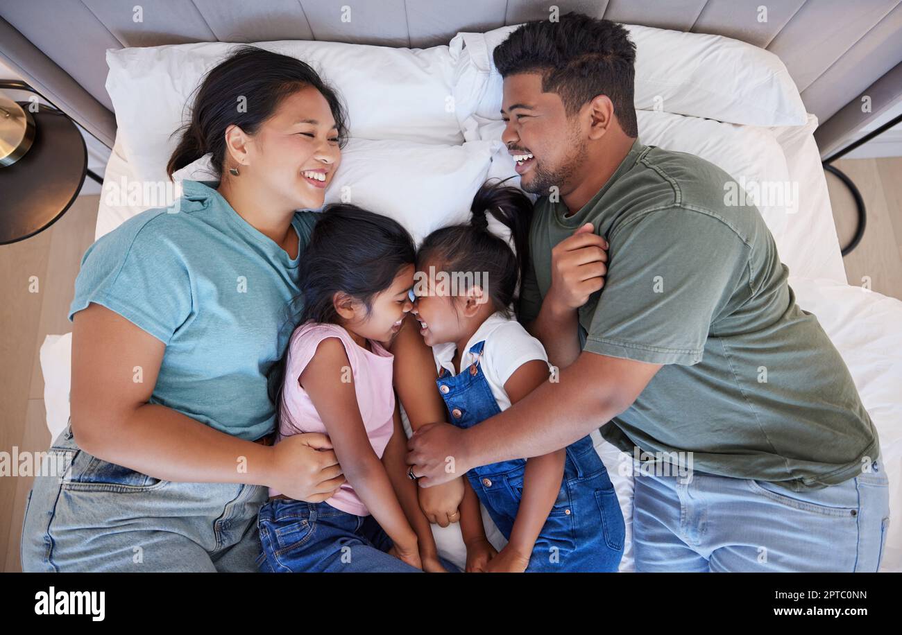 Family, bedroom and kids having fun bonding and lying in bed with their happy parents while ...