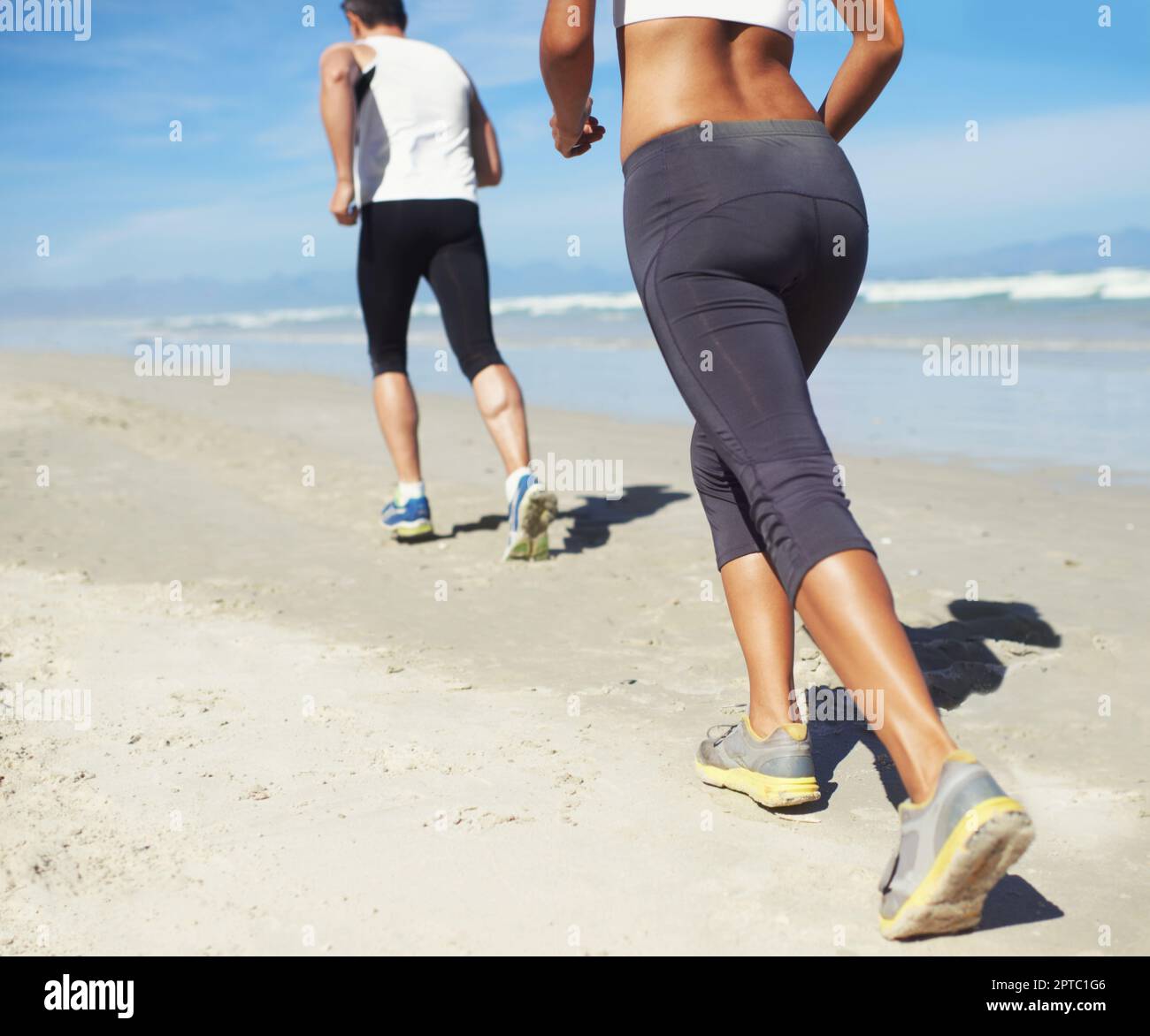 Getting fit together. two people running on the beach Stock Photo - Alamy