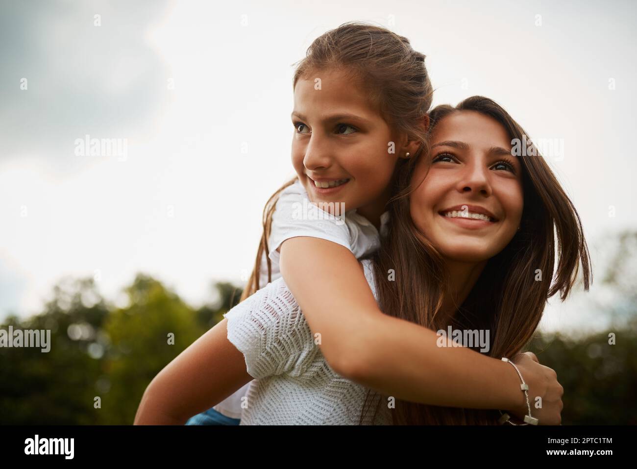Sisters are there to support one another. a young girl giving her younger sister a piggyback ...