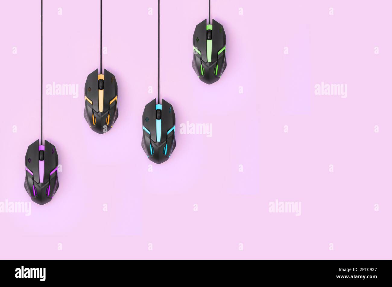 Several computer mice hang on a pastel pink background. The concept of ...