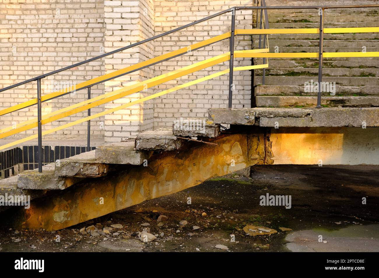 old concrete steps with yellow metal railings leading in to the ...
