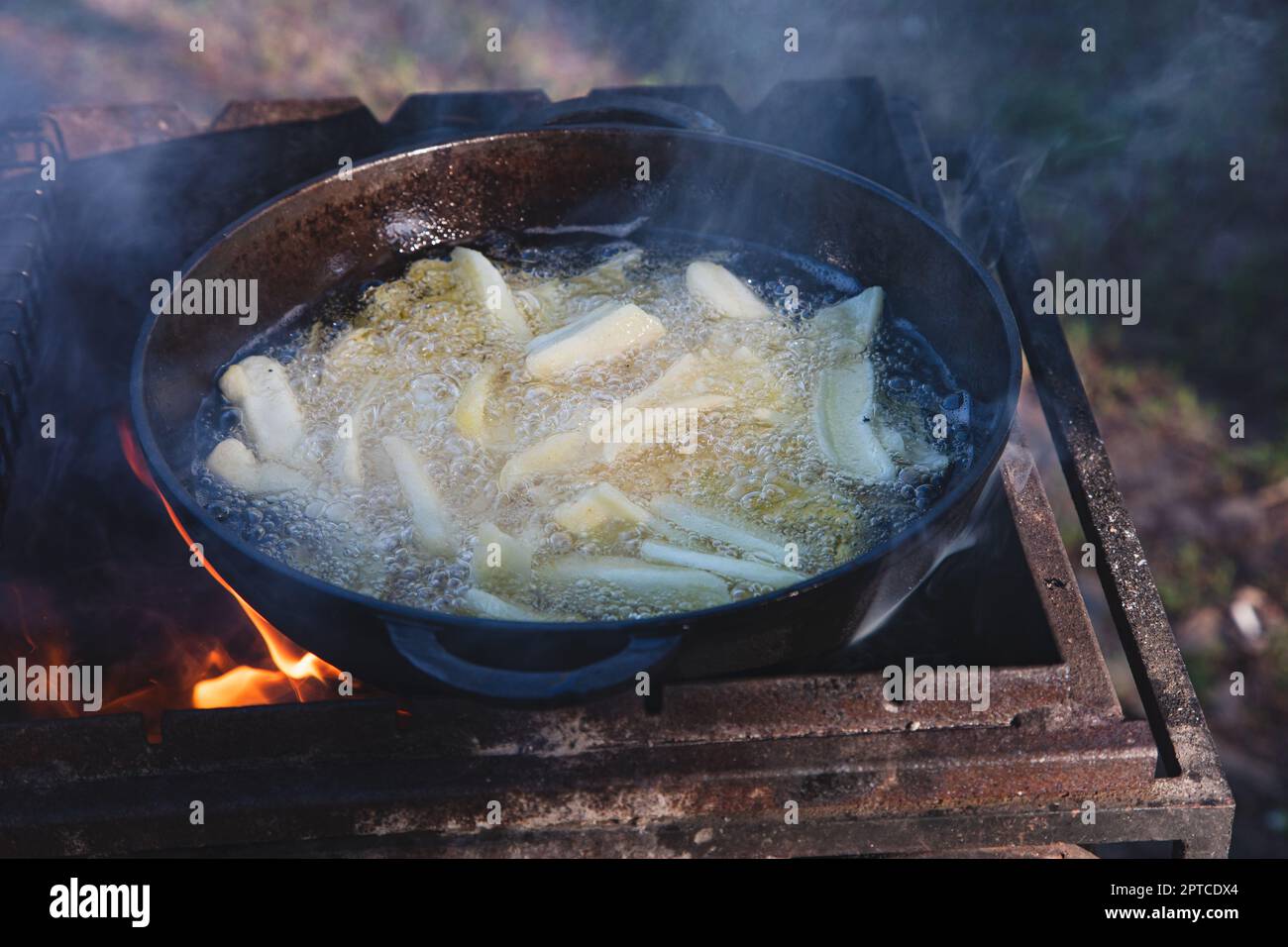 the process of cooking french fries on a fire in a cauldron. time for a ...