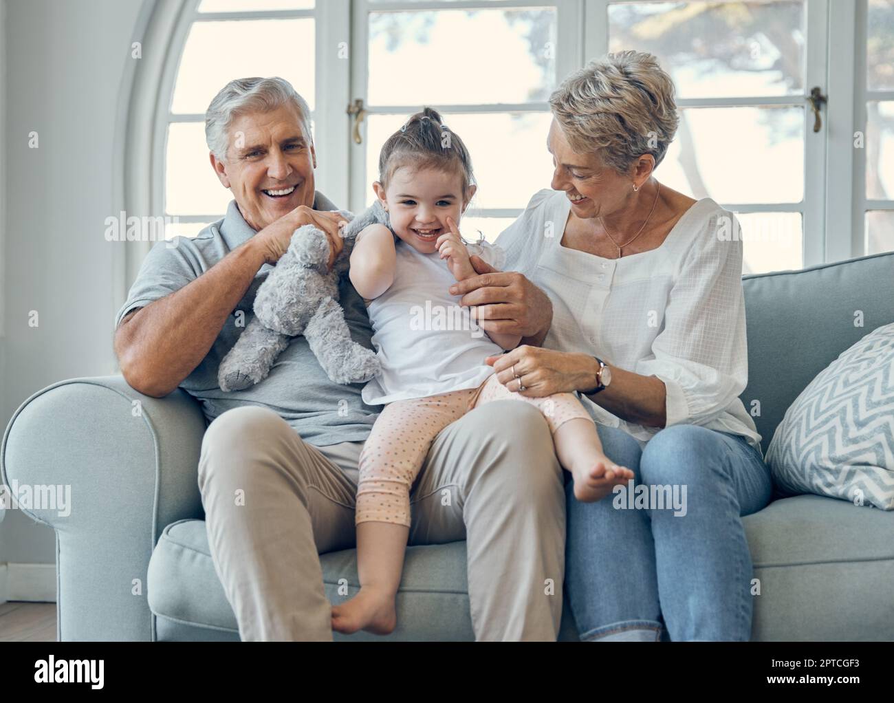 Family, grandmother and grandfather with girl on sofa, having fun and ...
