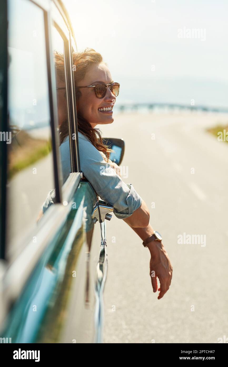 The freedom of the open road. an attractive woman hanging out of a car ...