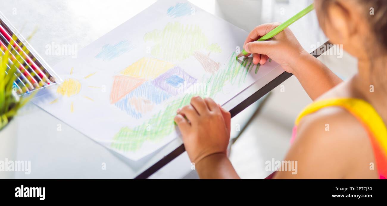 Asian cute kid preschooler sit on table smile she draw country house ...