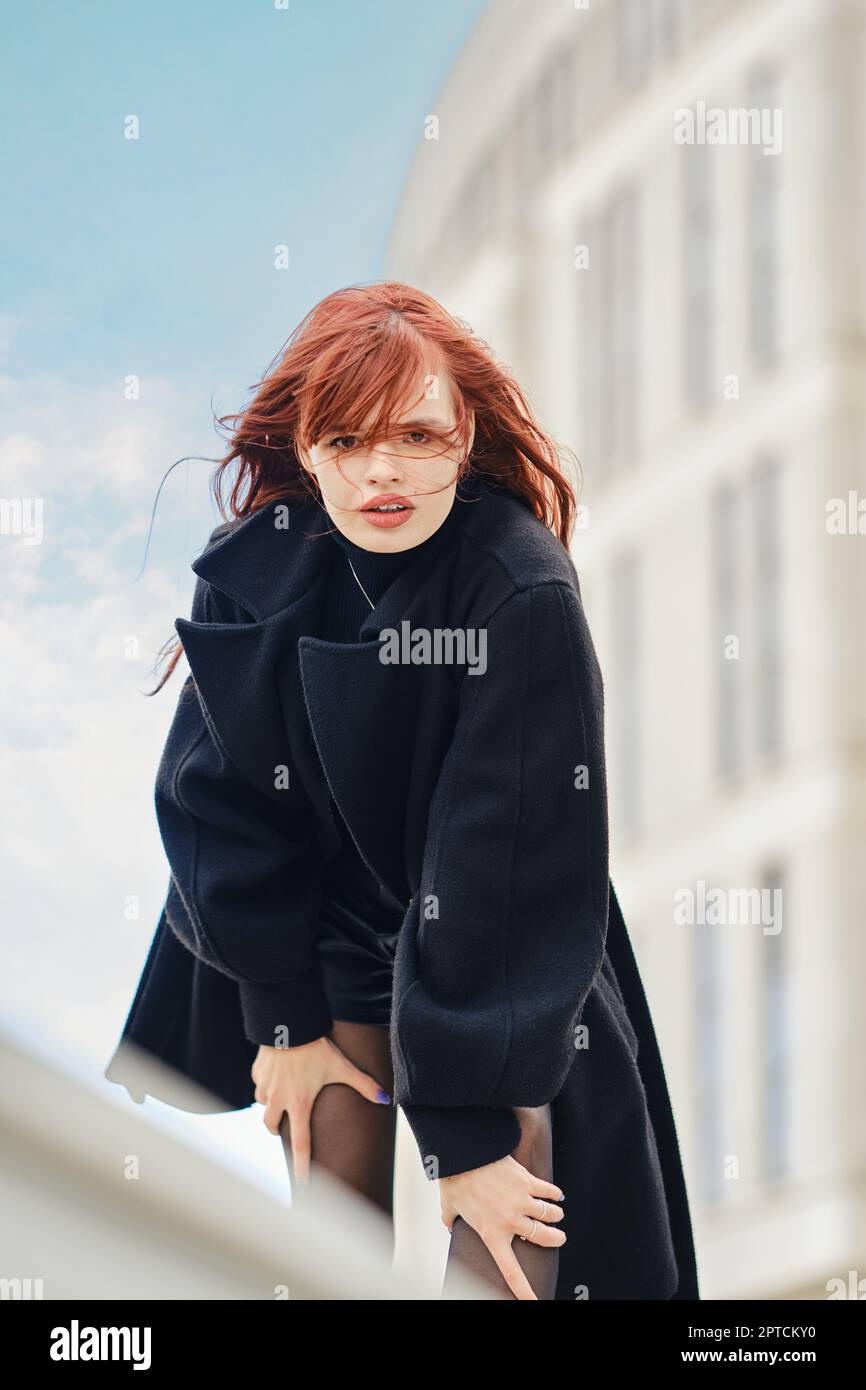 Tense young woman has her hands on her knees and is staring intently ...