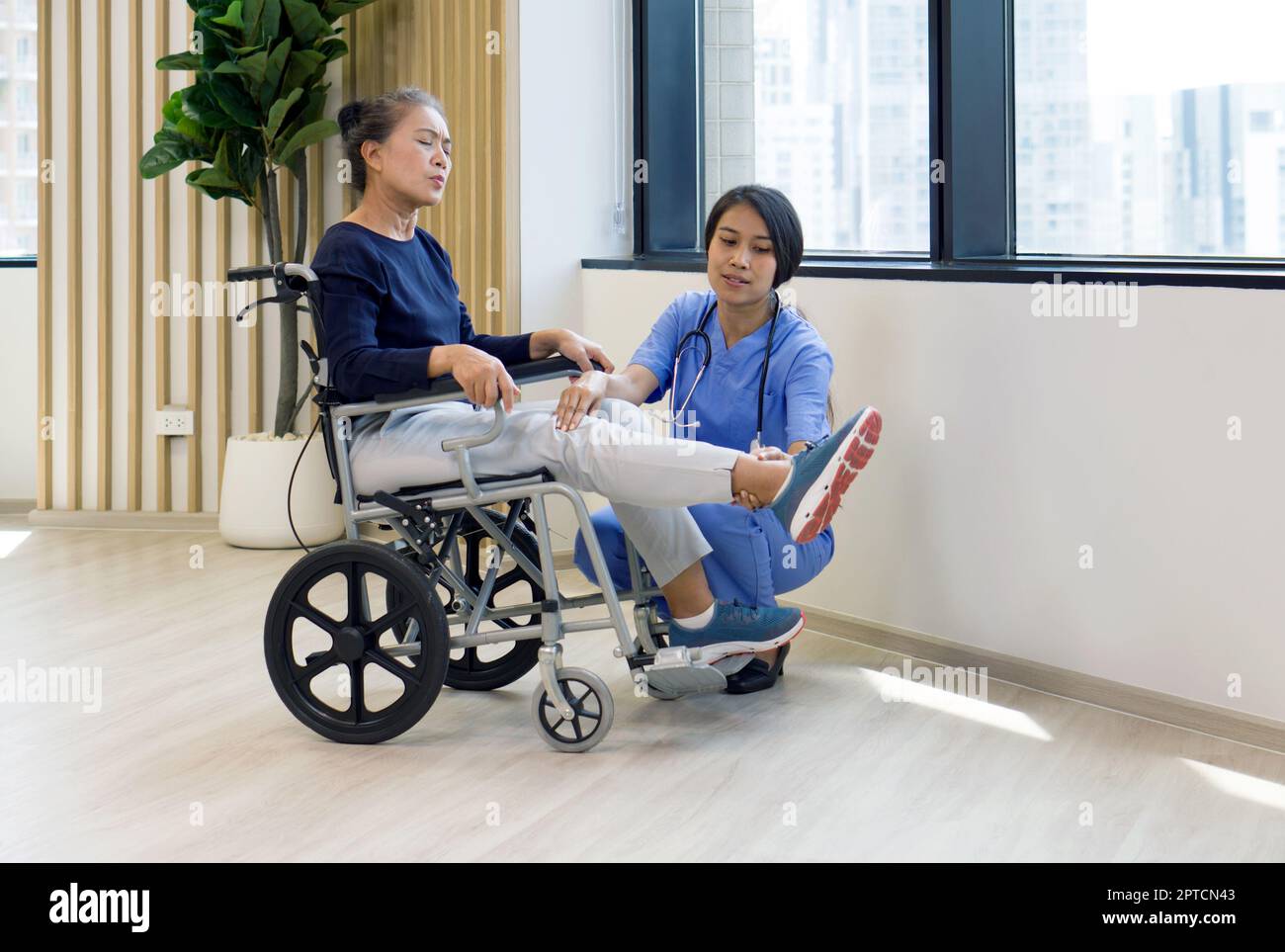 Young asian physical therapist in blue uniform help an elderly patient ...