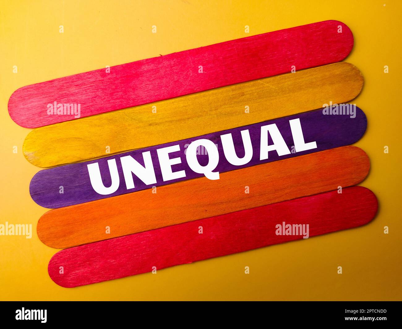 Colored wooden stick with the word UNEQUAL on yellow background Stock ...