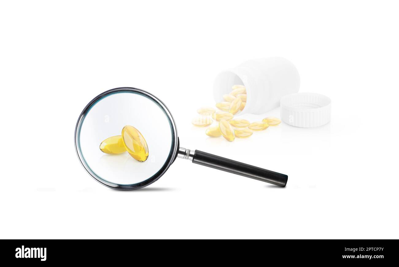 Capsules with yellow medicine and a magnifying glass on a white ...