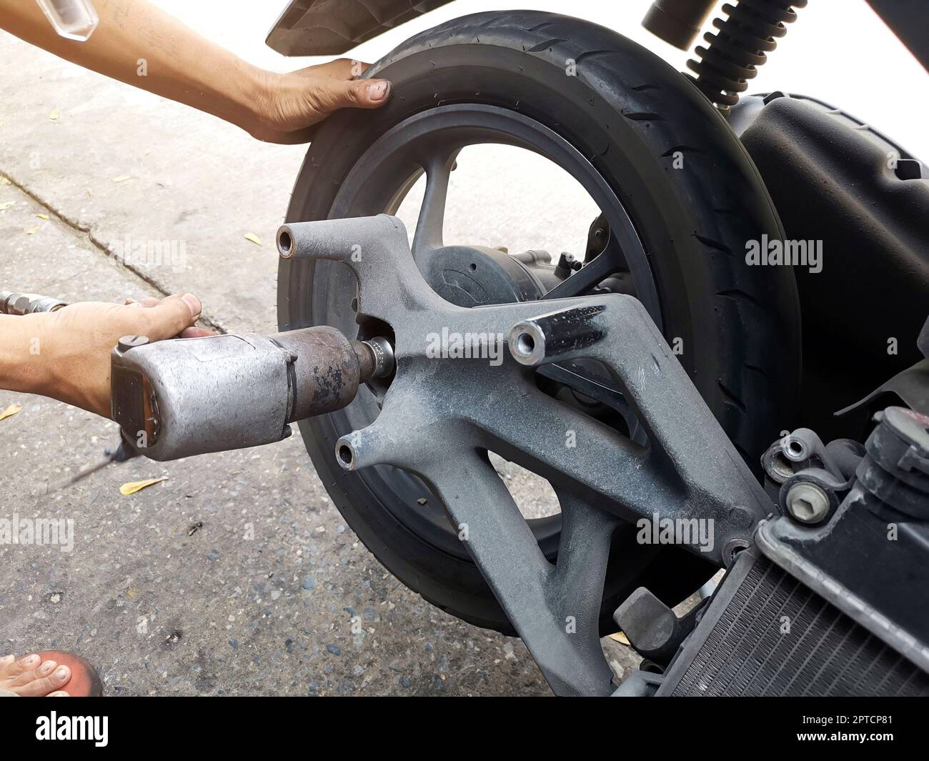 Close up of a motorcycle mechanic using an air gun to loosen the wheel ...