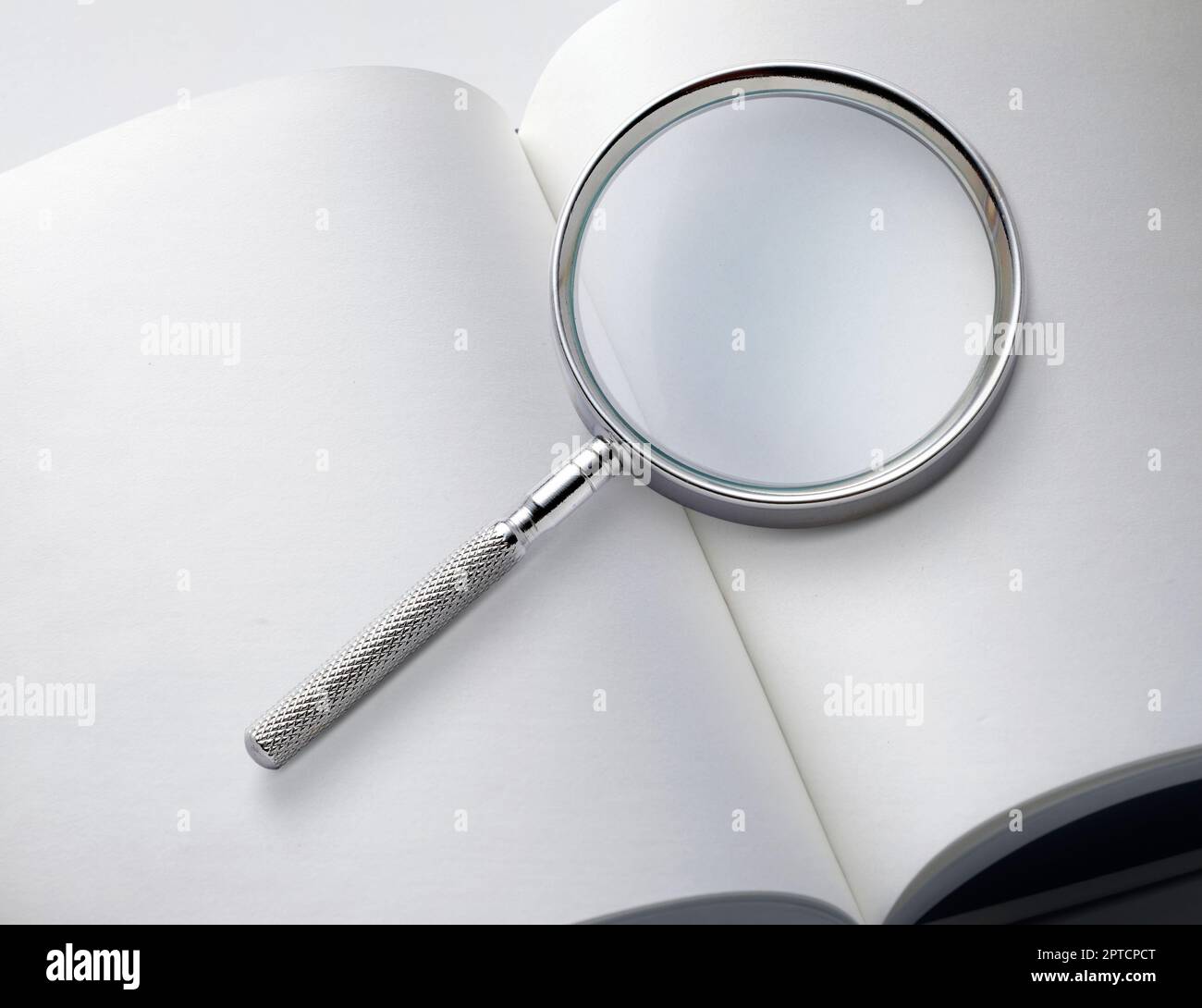 Open book closeup with turning pages and magnifying loupe. book in hard cover. Studying and ...