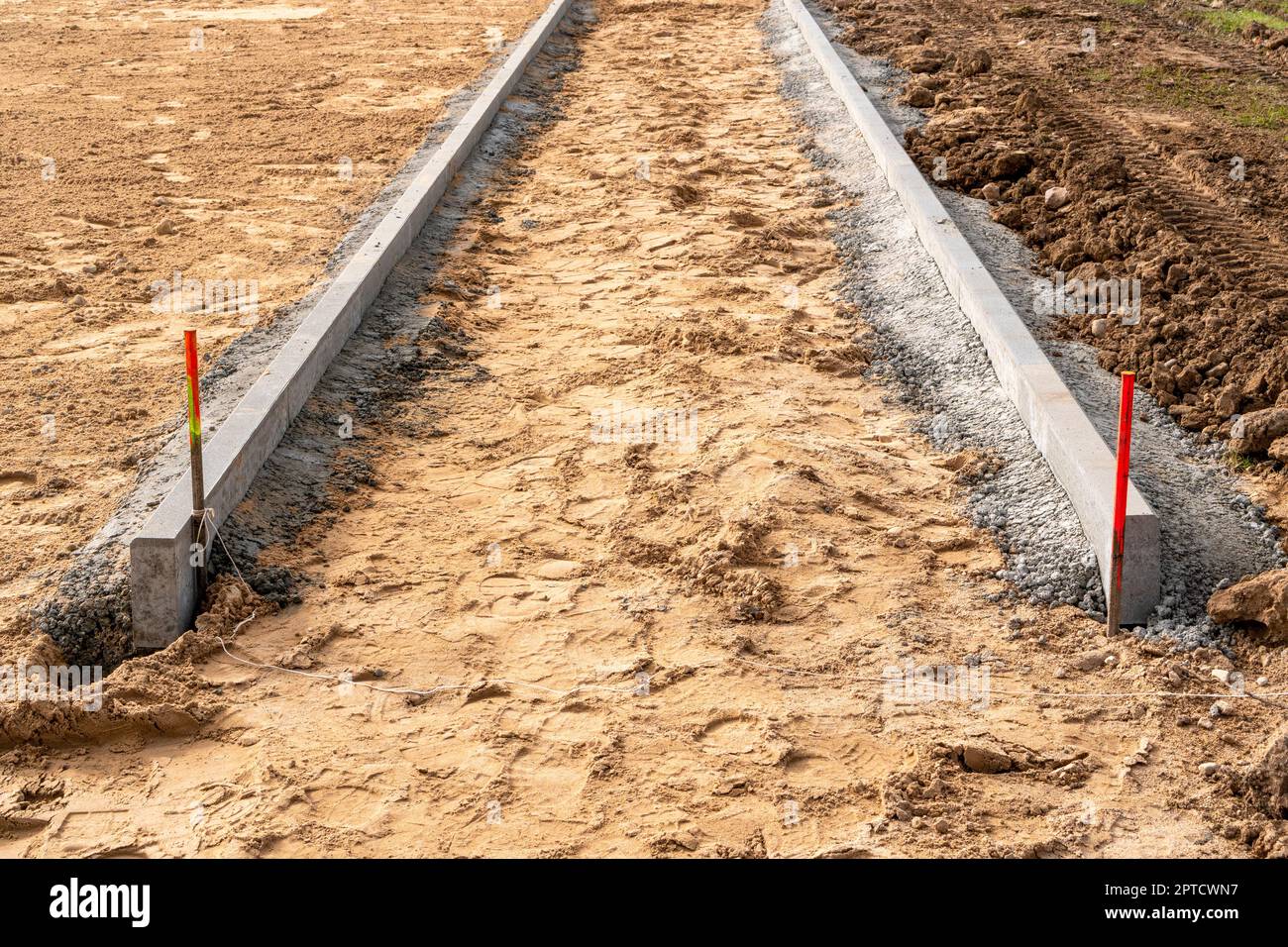 A sidewalk is under construction, a concrete curb is being installed ...